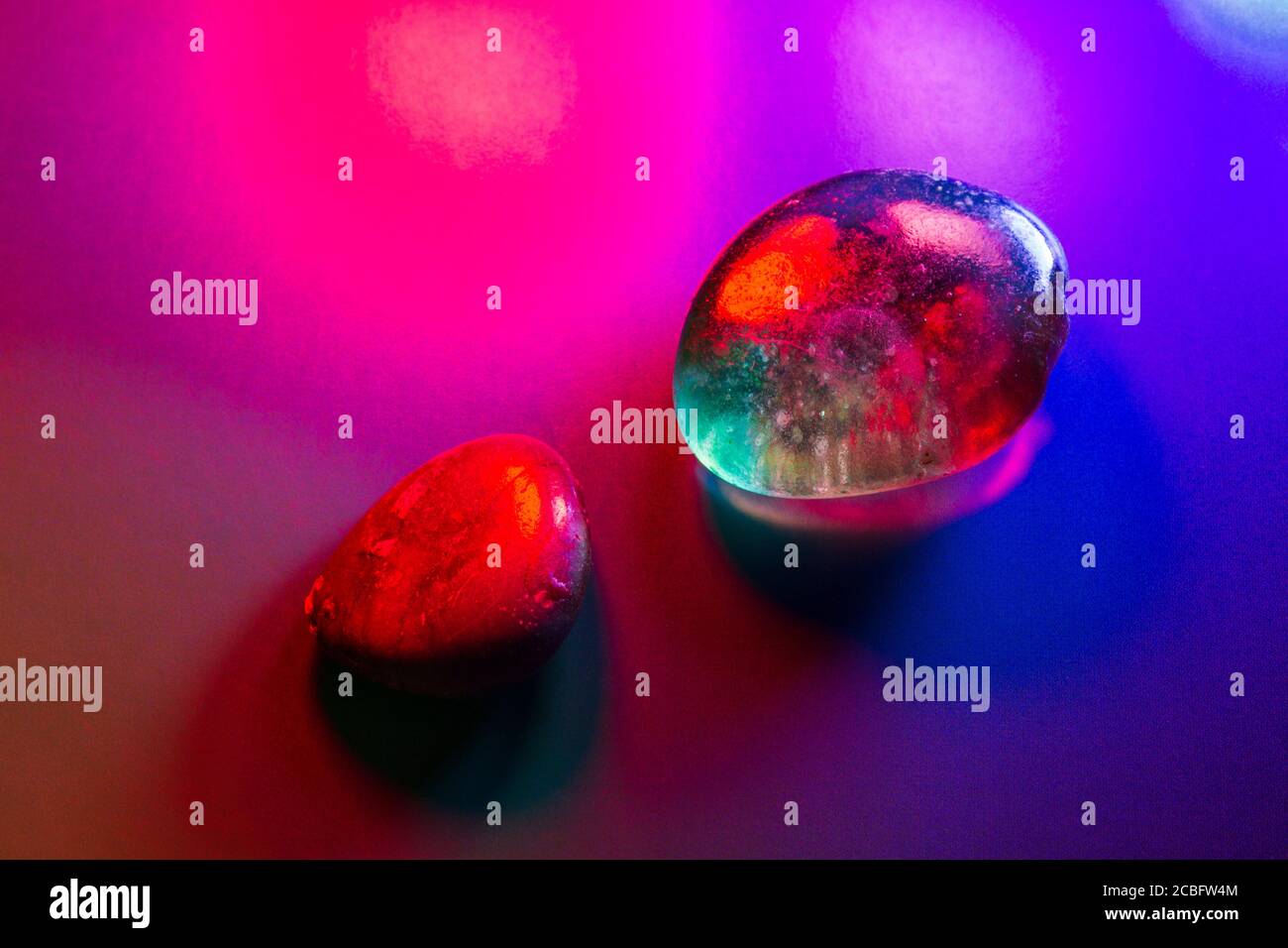Two tumbled mineral gems colorfully illuminated showing abstract ...