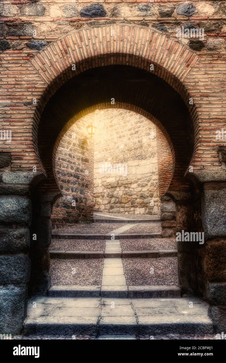 Ancient Moorish stone arch that leads to a narrow alley, illuminated by ...