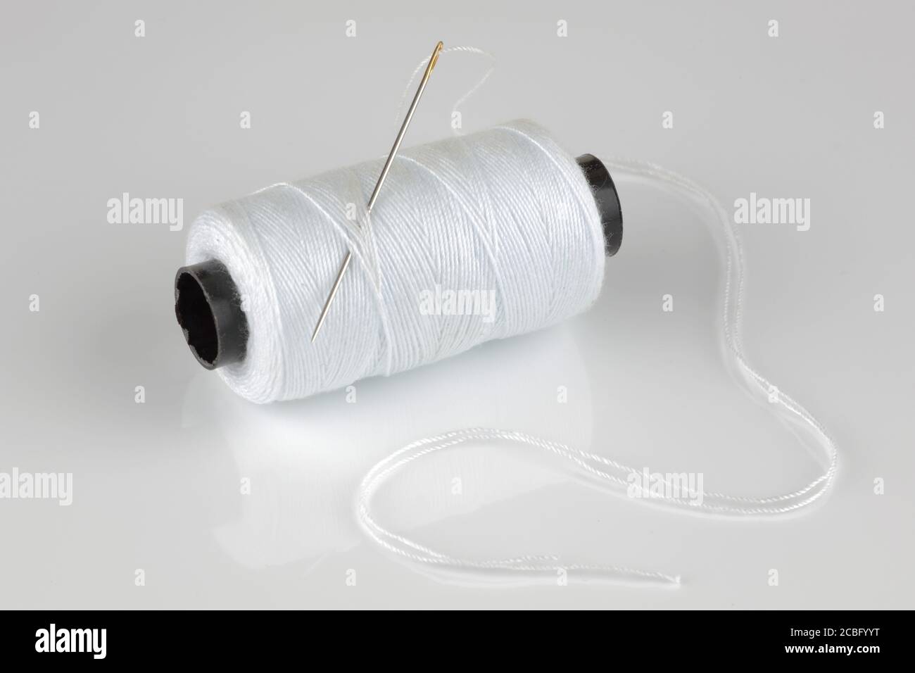 white cotton reel and needle with reflection Stock Photo - Alamy