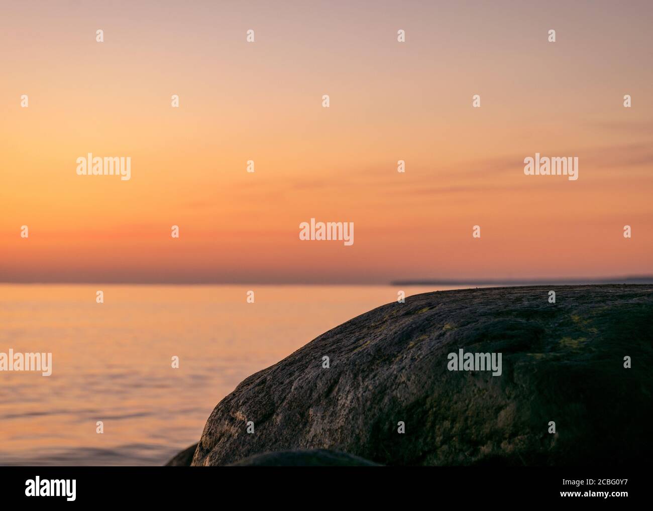 orange sunset by the sea, black stone silhouettes against the sea ...