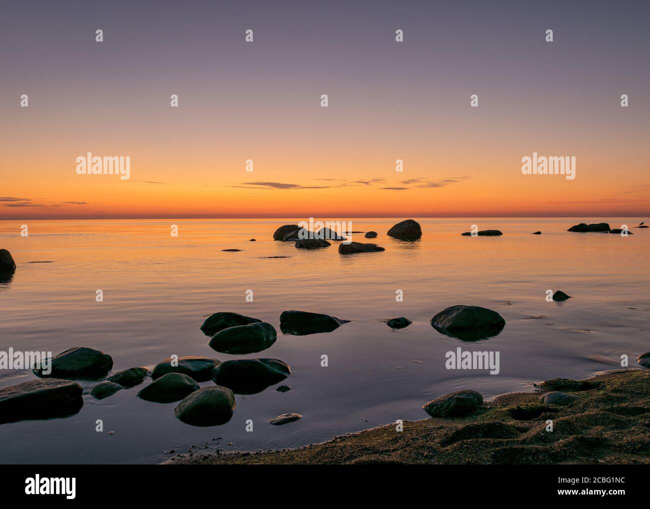 orange sunset by the sea, black stone silhouettes against the sea ...