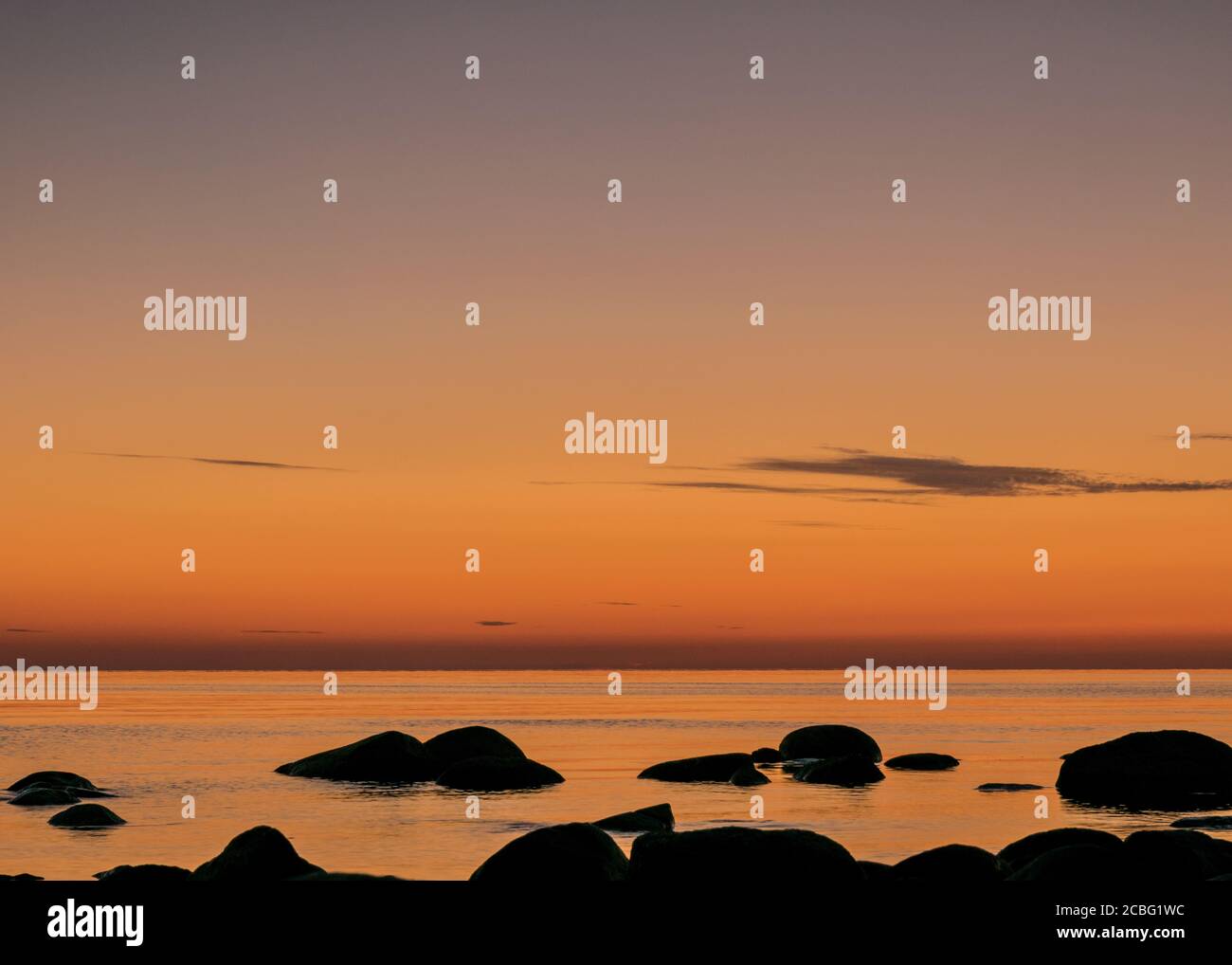 orange sunset by the sea, black stone silhouettes against the sea ...