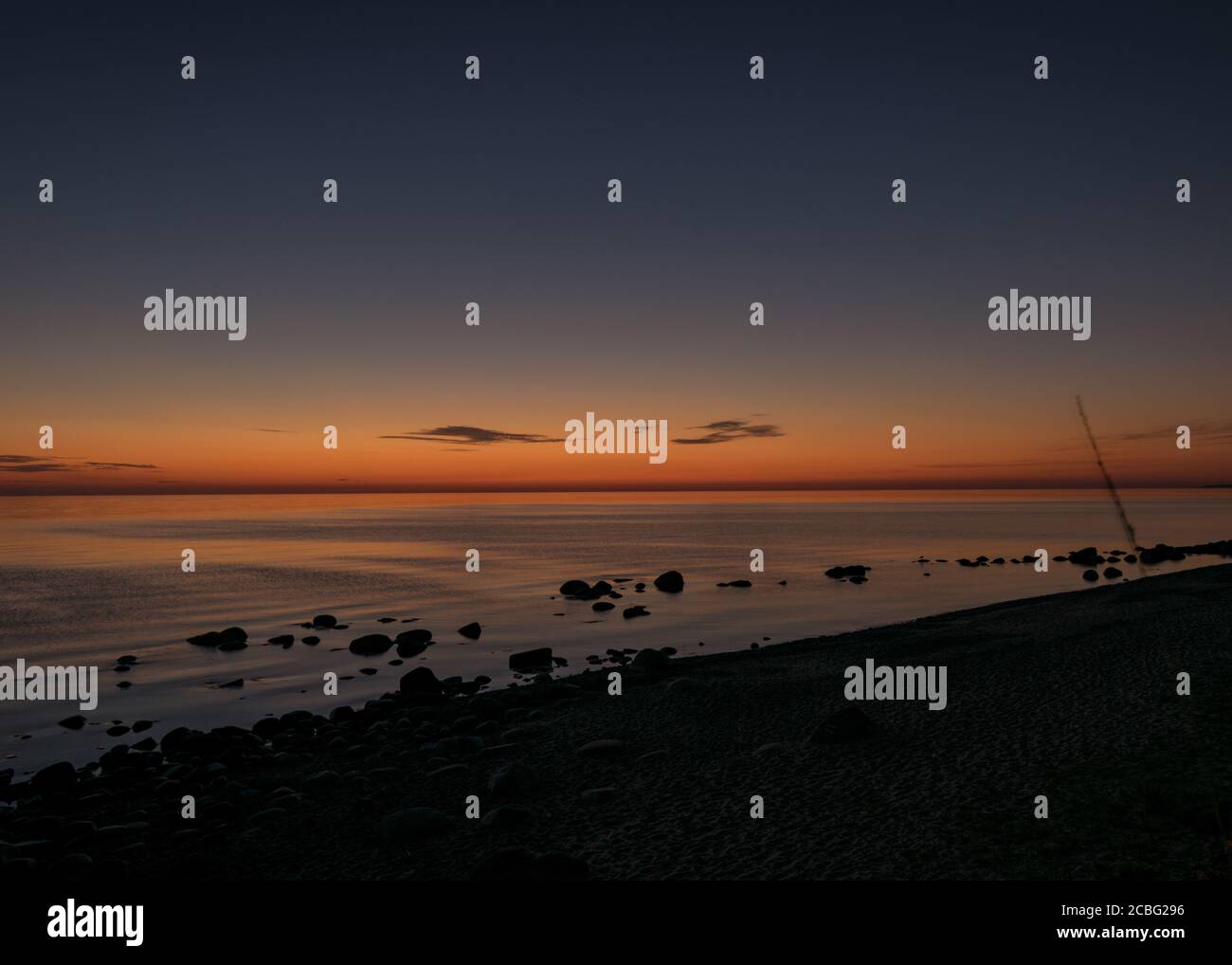 orange sunset by the sea, black stone silhouettes against the sea ...