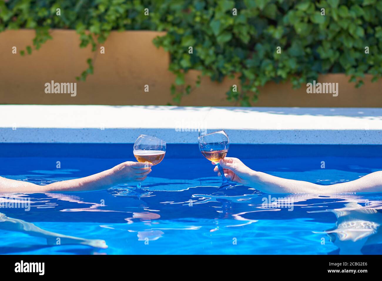 Two people toast in a pool. Closed shot of toasting hands Stock Photo ...