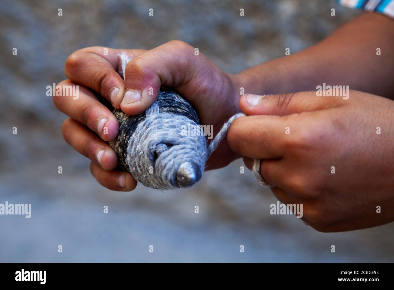 A boy rolling the string in a wooden spinning top on the road. Old ...
