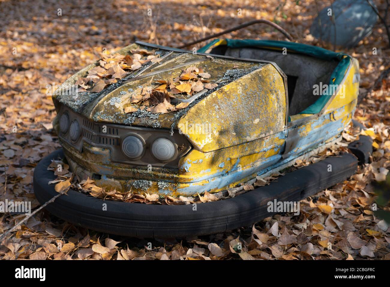Yellow rusty radioactive metal car among autumn leaves in the park of ...
