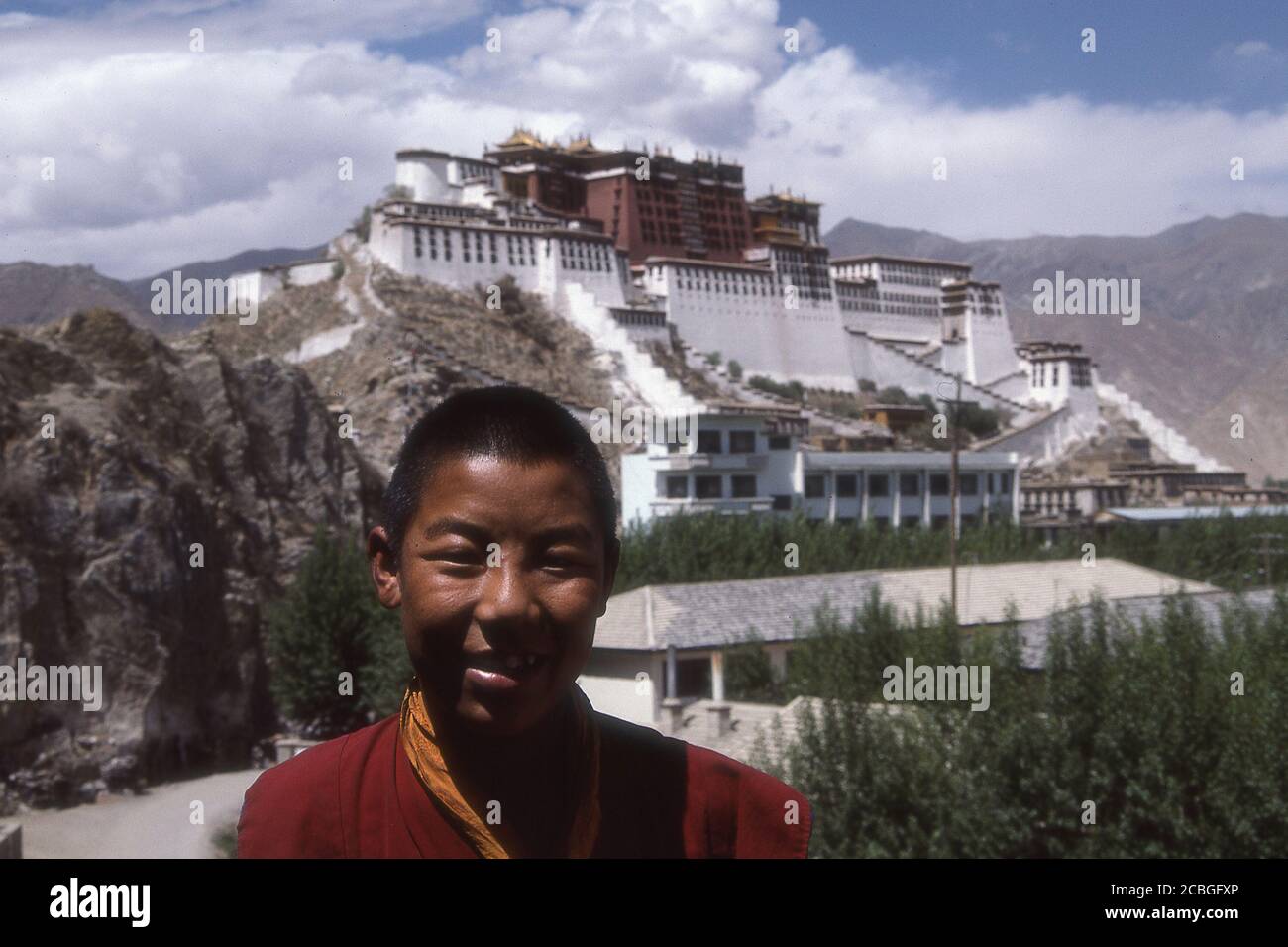 TIBET - NOVICE AT PALALUBU TEMPLE, LHASA. POTALA PALACE IN BACKGROUND ...
