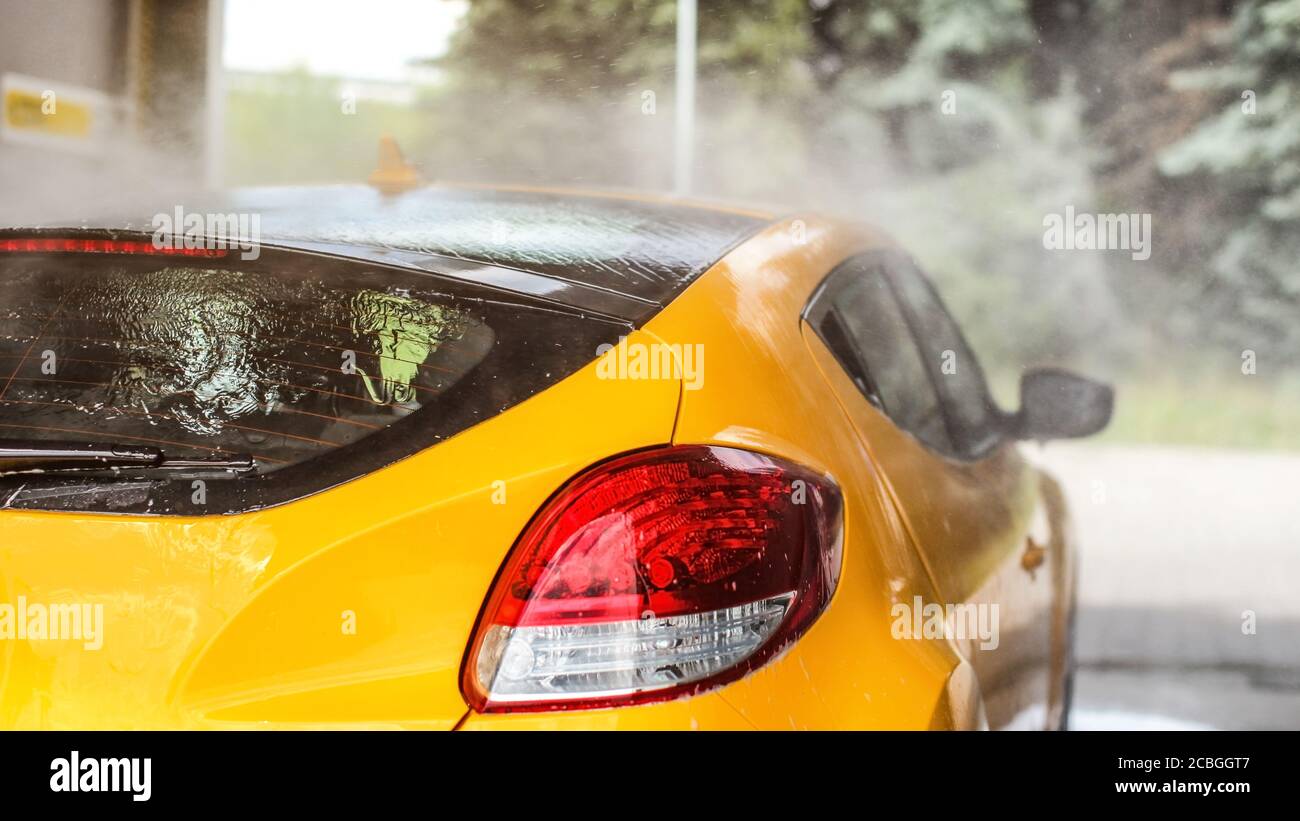 Roof and side of yellow car washed in self serve carwash, water ...