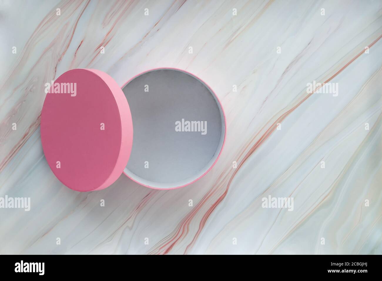Pink round box with open lid on elegant marble background. Round gift ...