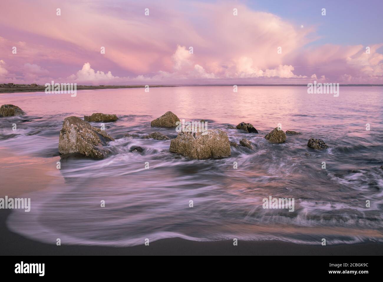 Wave Crashing Over Rocks on Ocean Beach with Pink Sunset Sky Stock ...