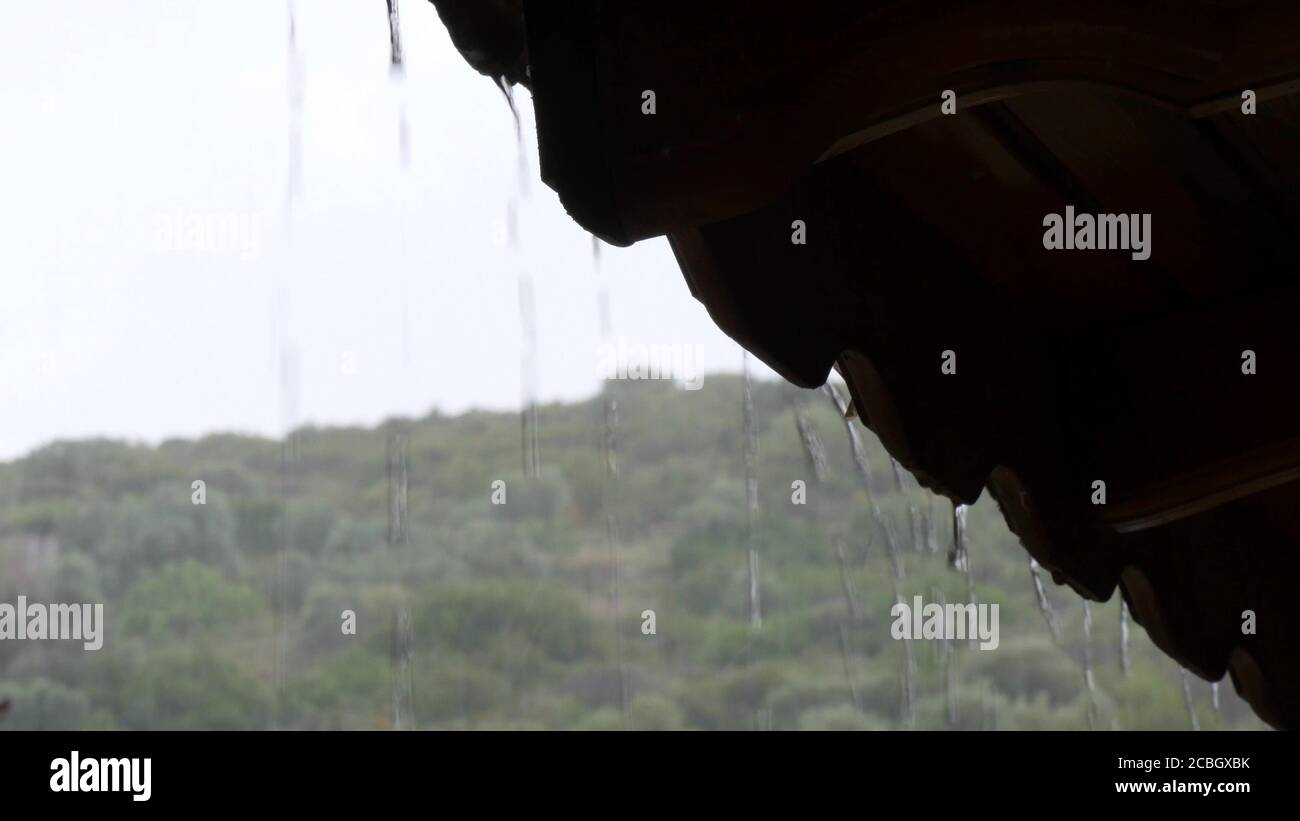 Rain drops falling from roof's eave during rain Stock Photo - Alamy