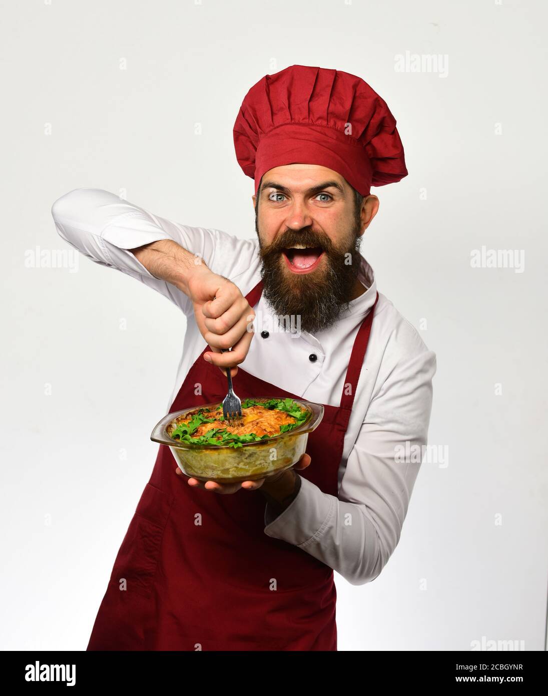 Chef holds bowl with potato casserole and fork in it. Cook with ...