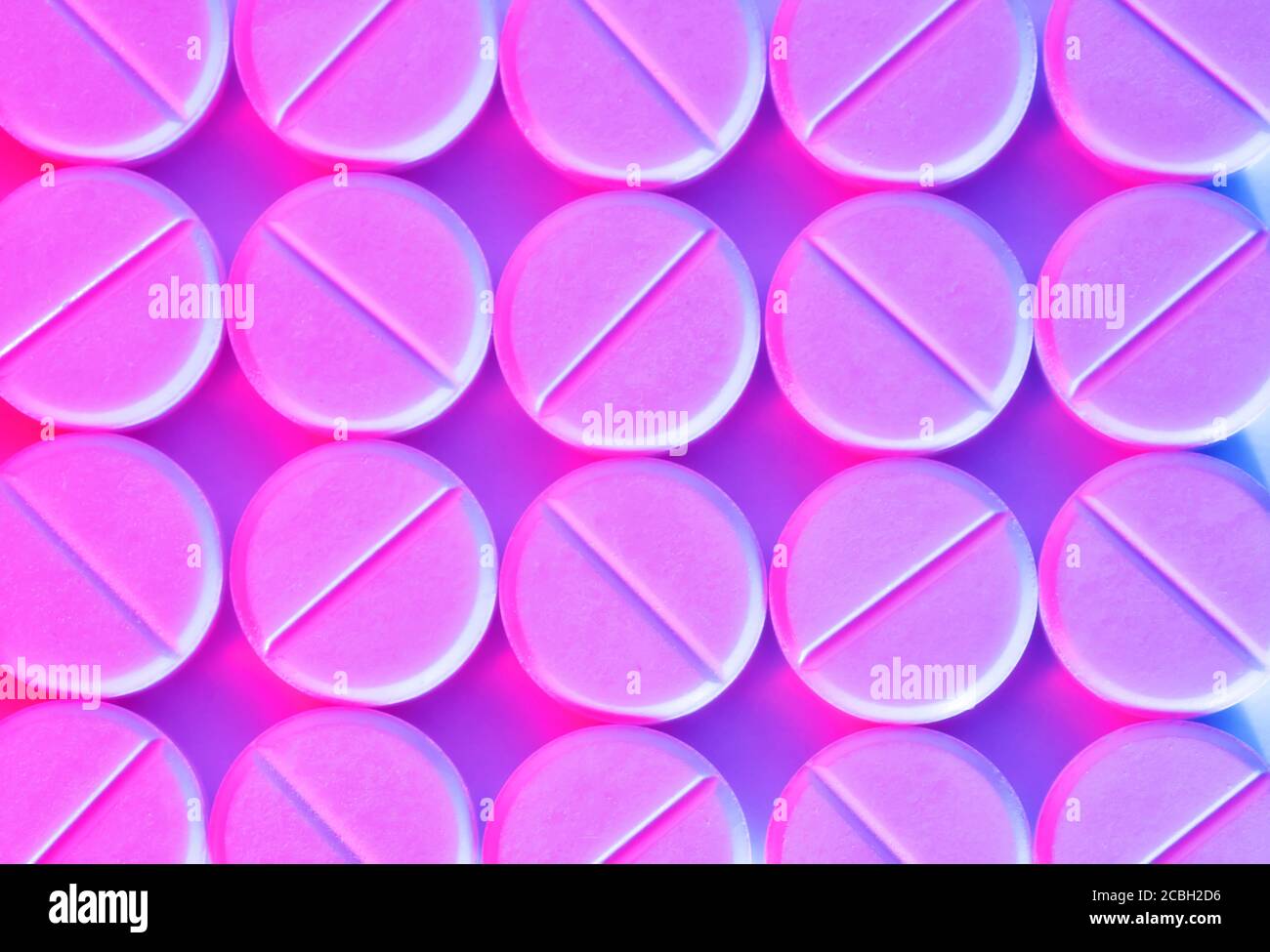 Geometric pattern of white round medical pills in purple light flash ...