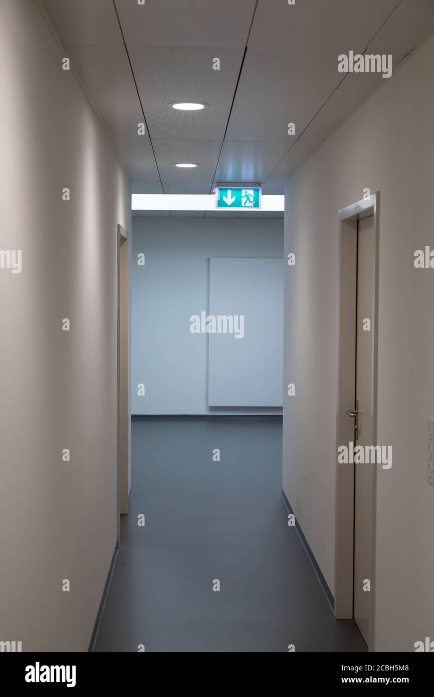 corridor with office rooms and green emergency exit sign Stock Photo ...