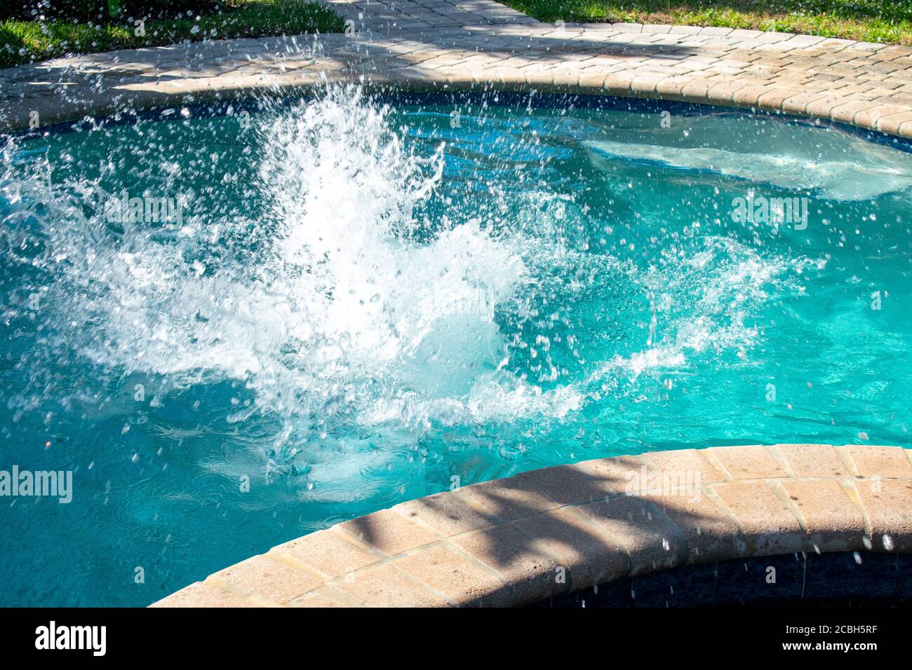A Large Splash of Water in a Swimming Pool Caused By a Boy Jumping Into ...