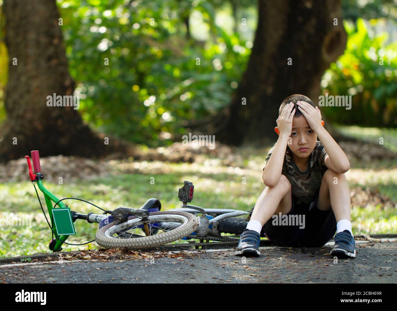 Asian boy worried after a bicycle accident in the park Stock Photo - Alamy