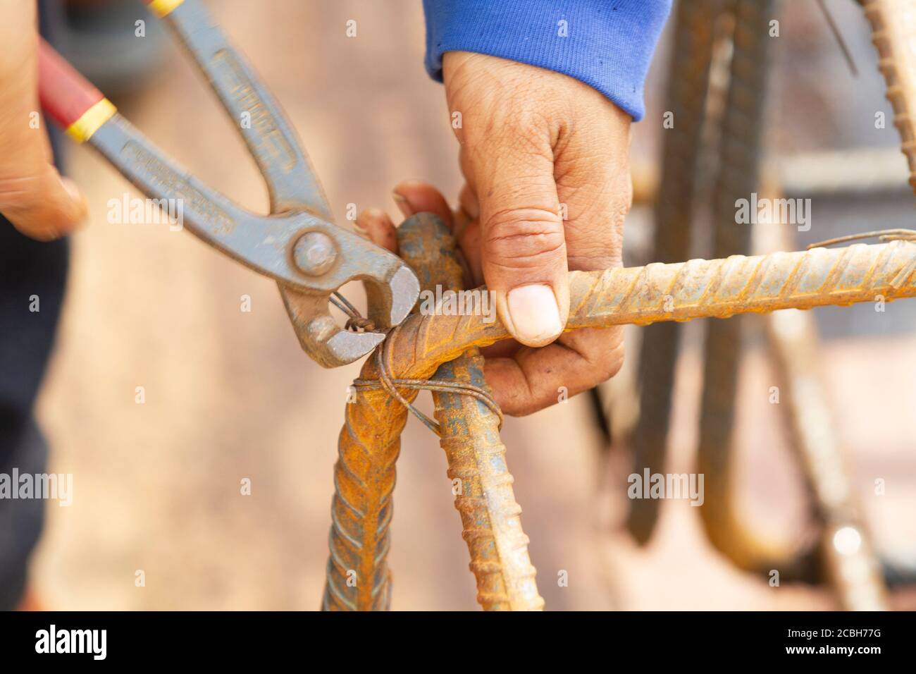 Close up image of construction worker securing steel bars with wire rod ...