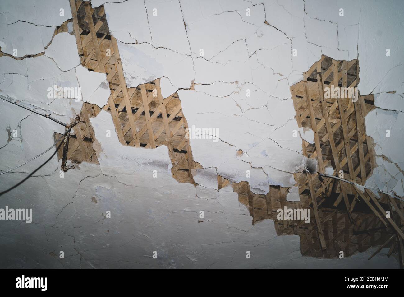 Dilapidated ceiling of an old house. damaged wall with a hole with ...