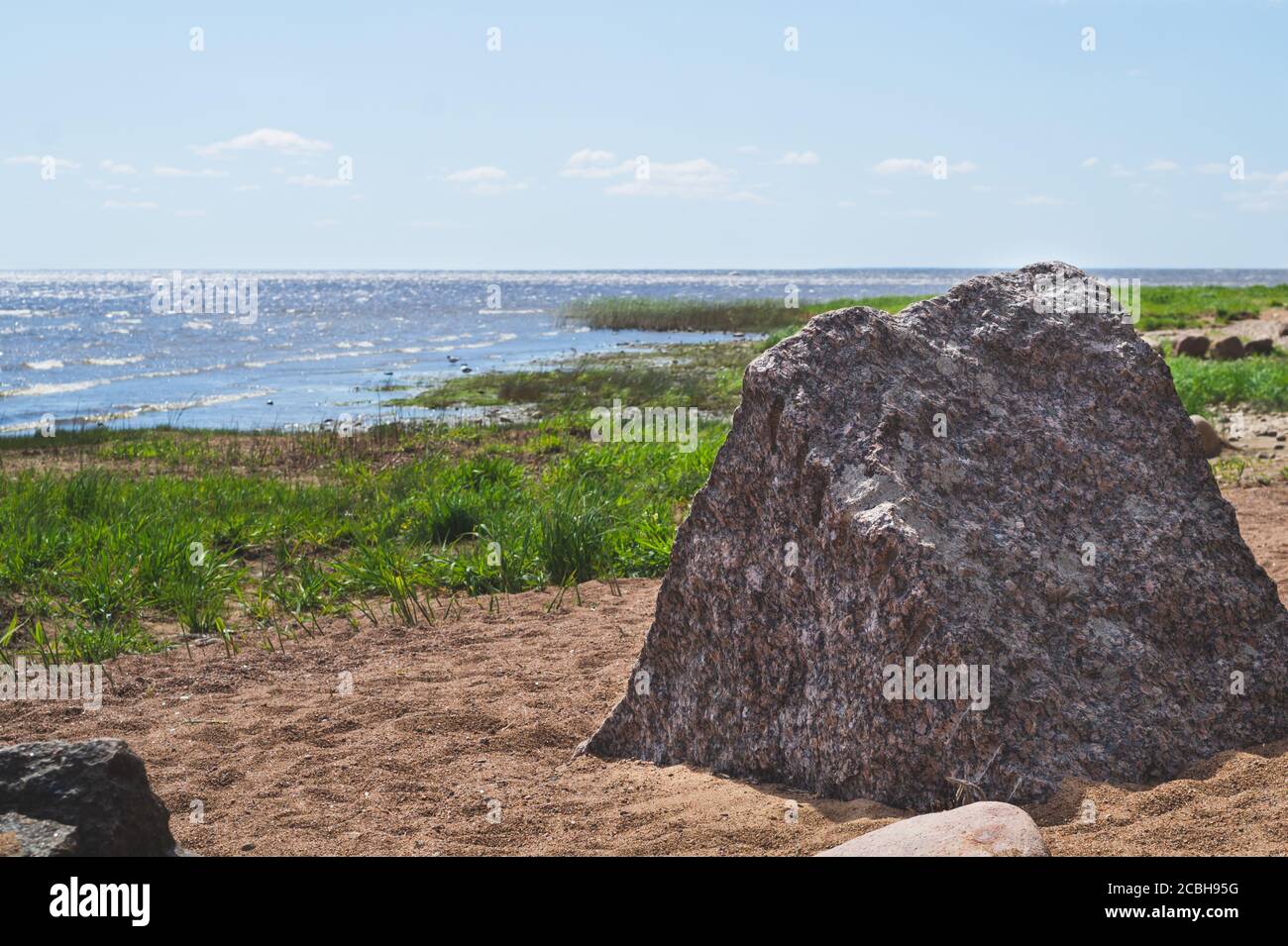 Big stone in the triangular prism shape on the sea shore. boulder on ...