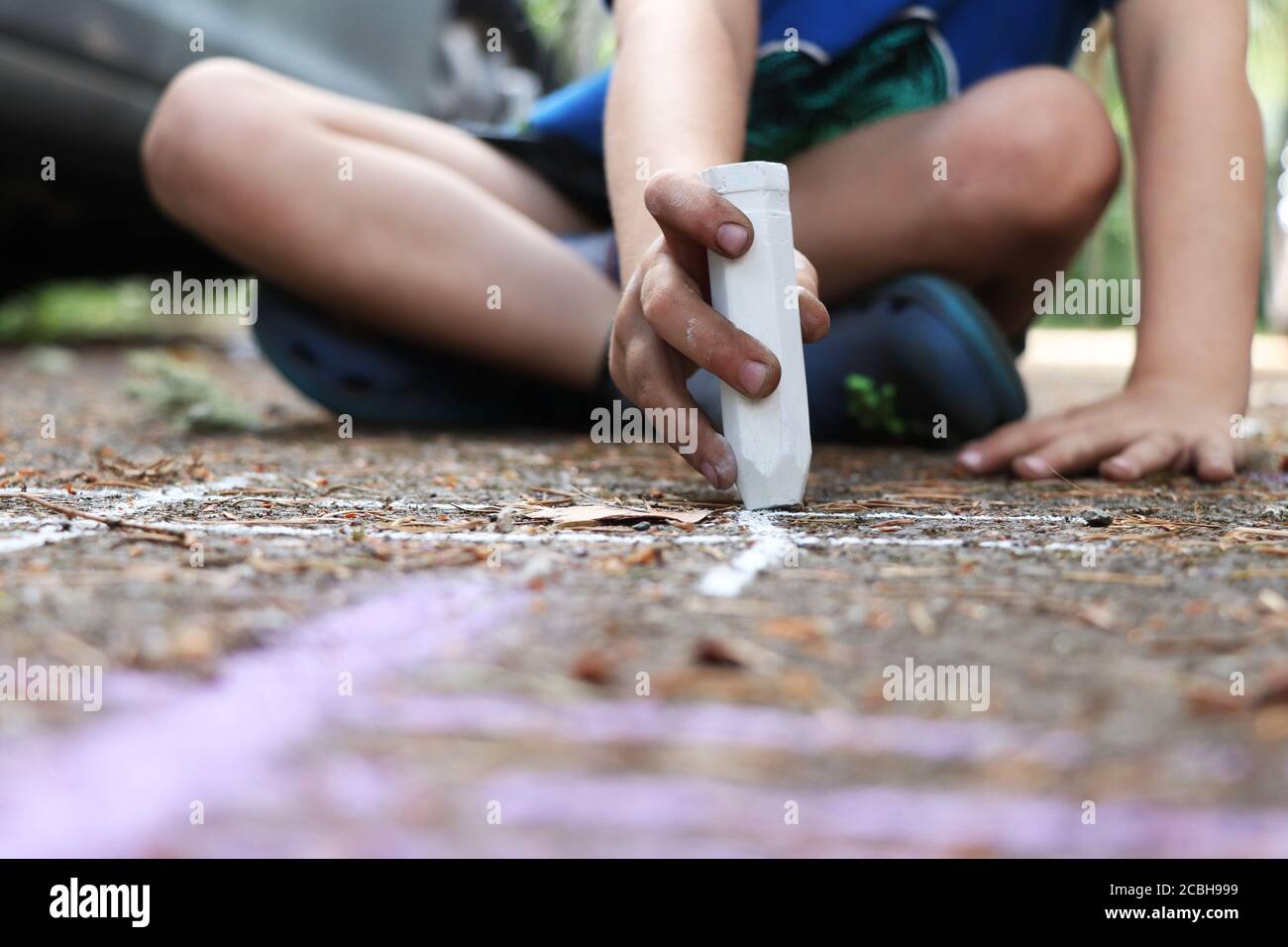 Toddler using chalk on a sidewalk Stock Photo - Alamy