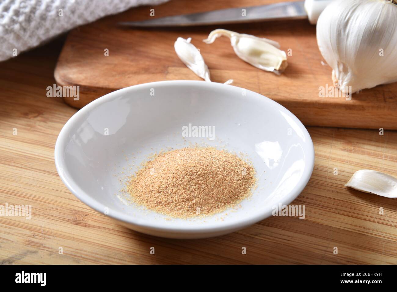 Roasted garlic powder in a spice dish with a fresh bulb of garlic Stock ...