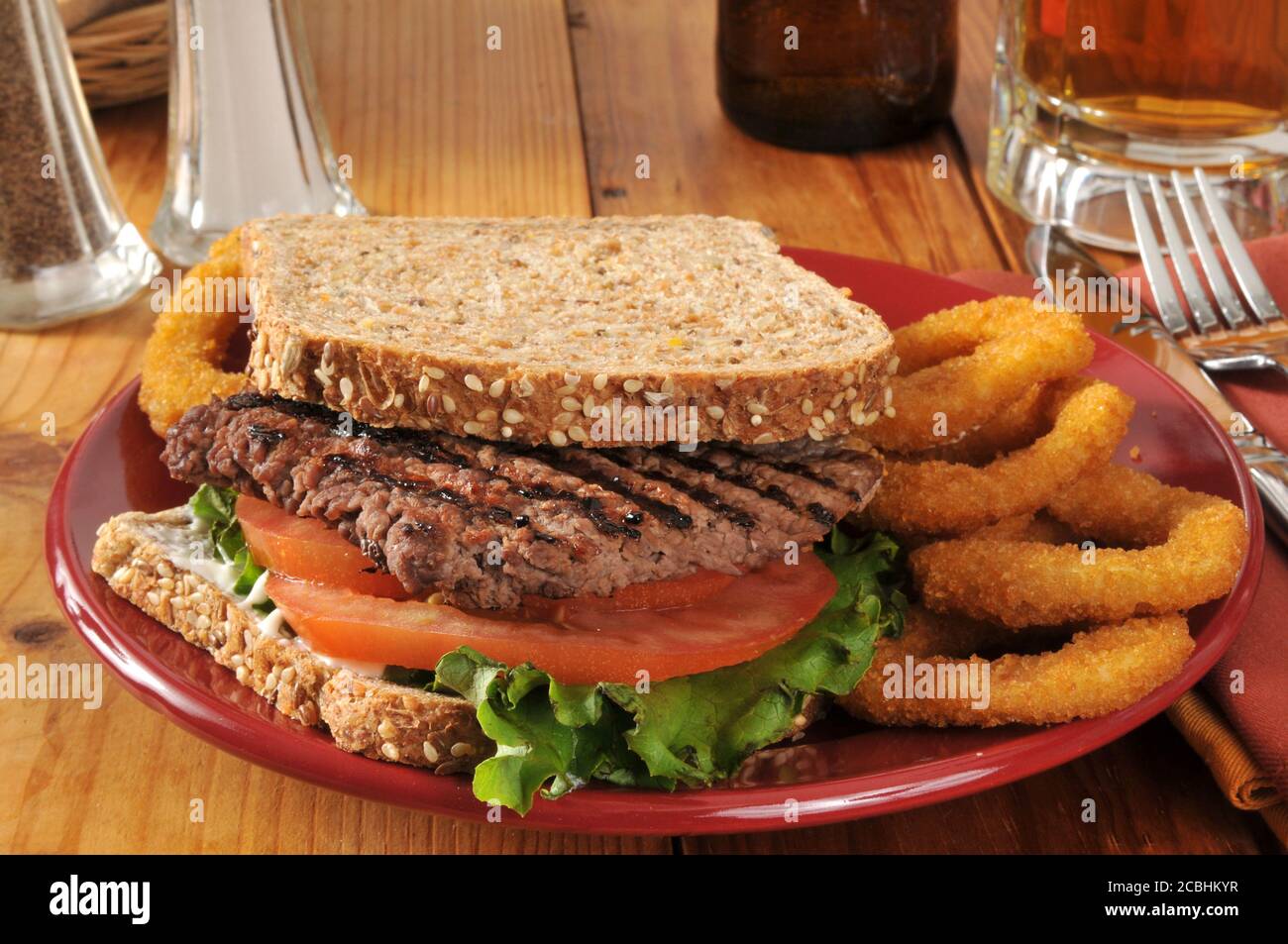 A cube steak sandwich with onion rings on sprouted nut and seed bread ...