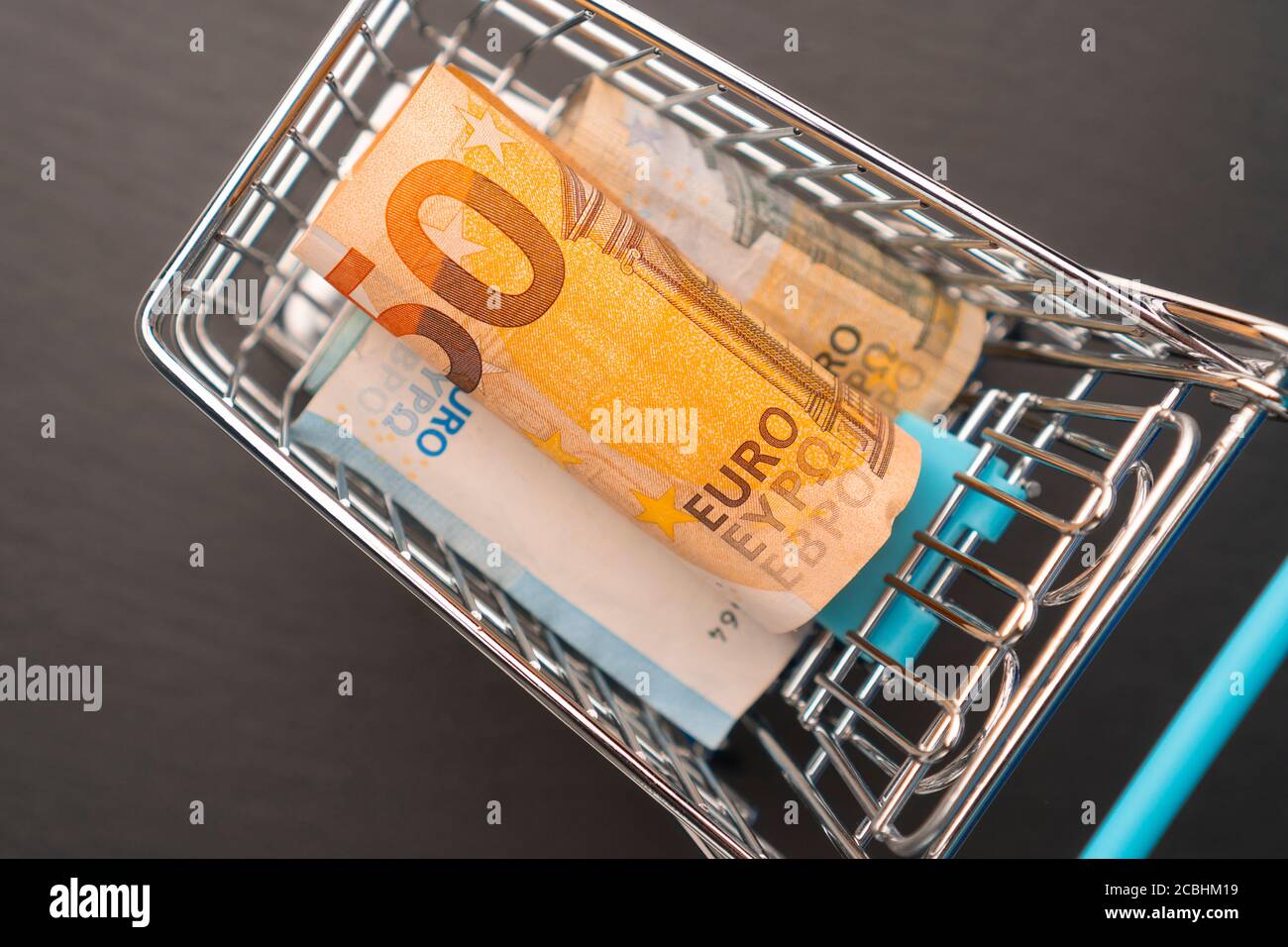 Rolled euro money in a supermarket shopping cart on a dark background ...