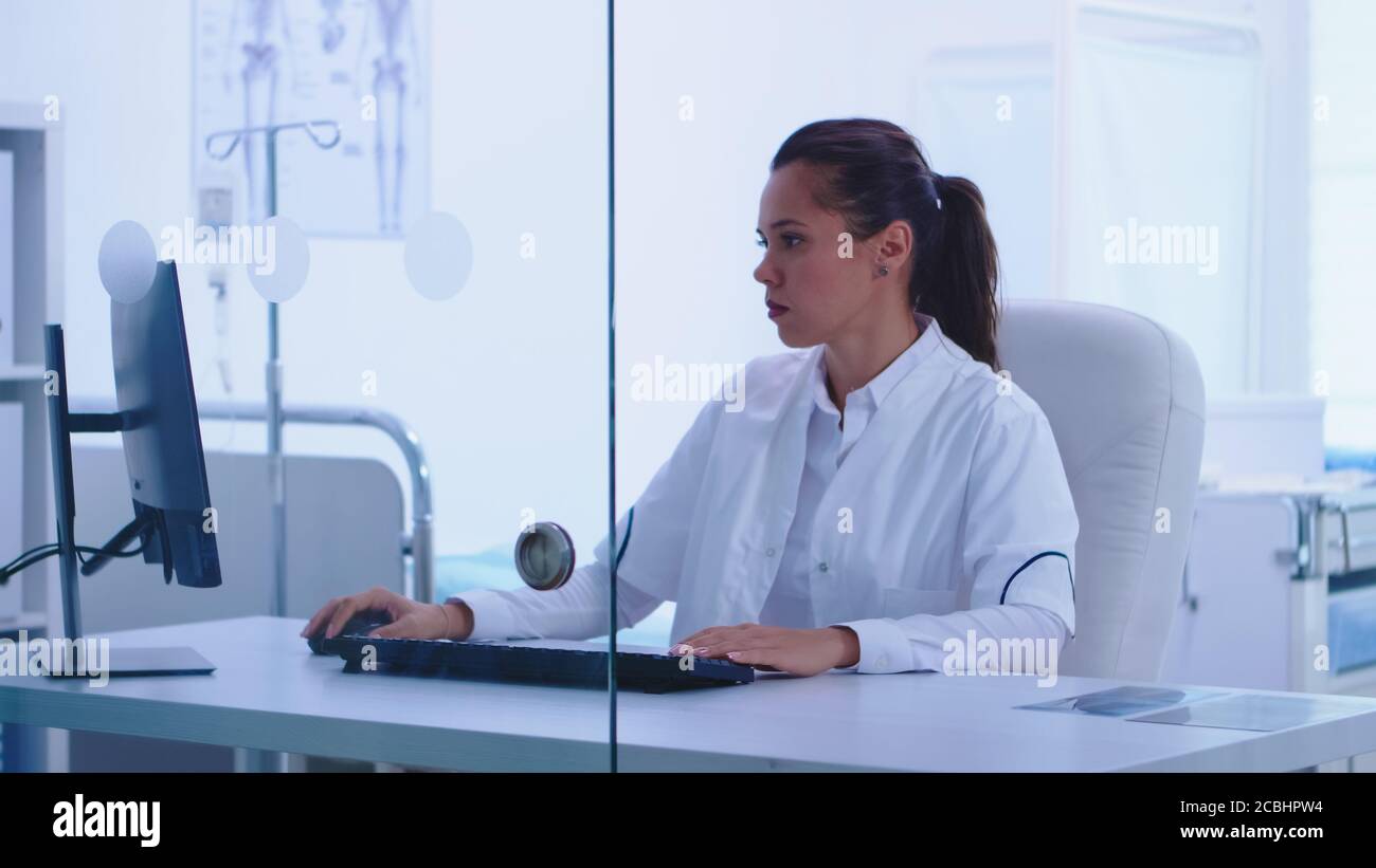 View through glass wall of doctor in cabinet while assistant giving ...