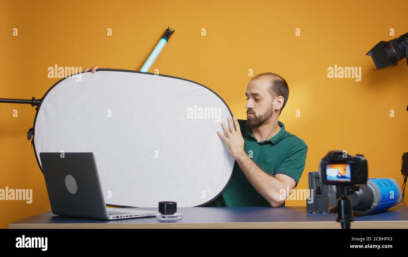Photographer recording vlog about white light reflector in studio ...