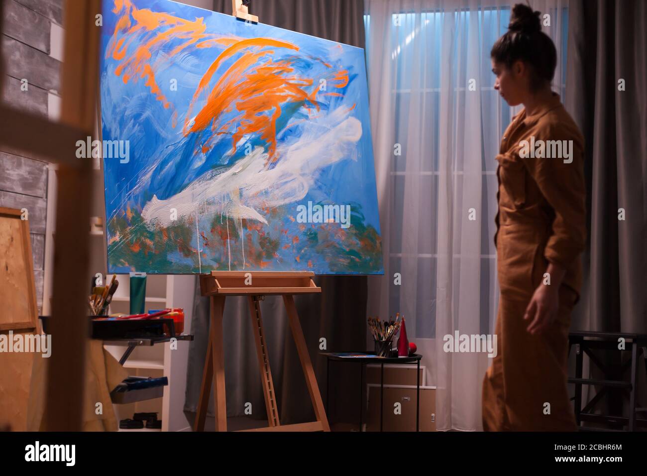 Artist woman checking her abstract painting in art workshop. Modern ...