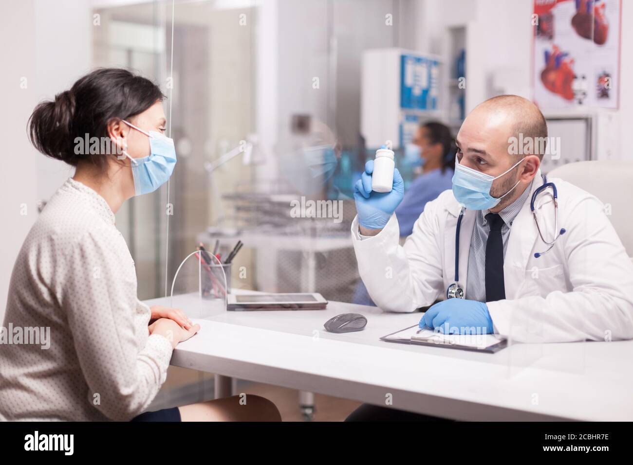 Doctor wearing protection mask against covid 19 showing bottle of pills ...