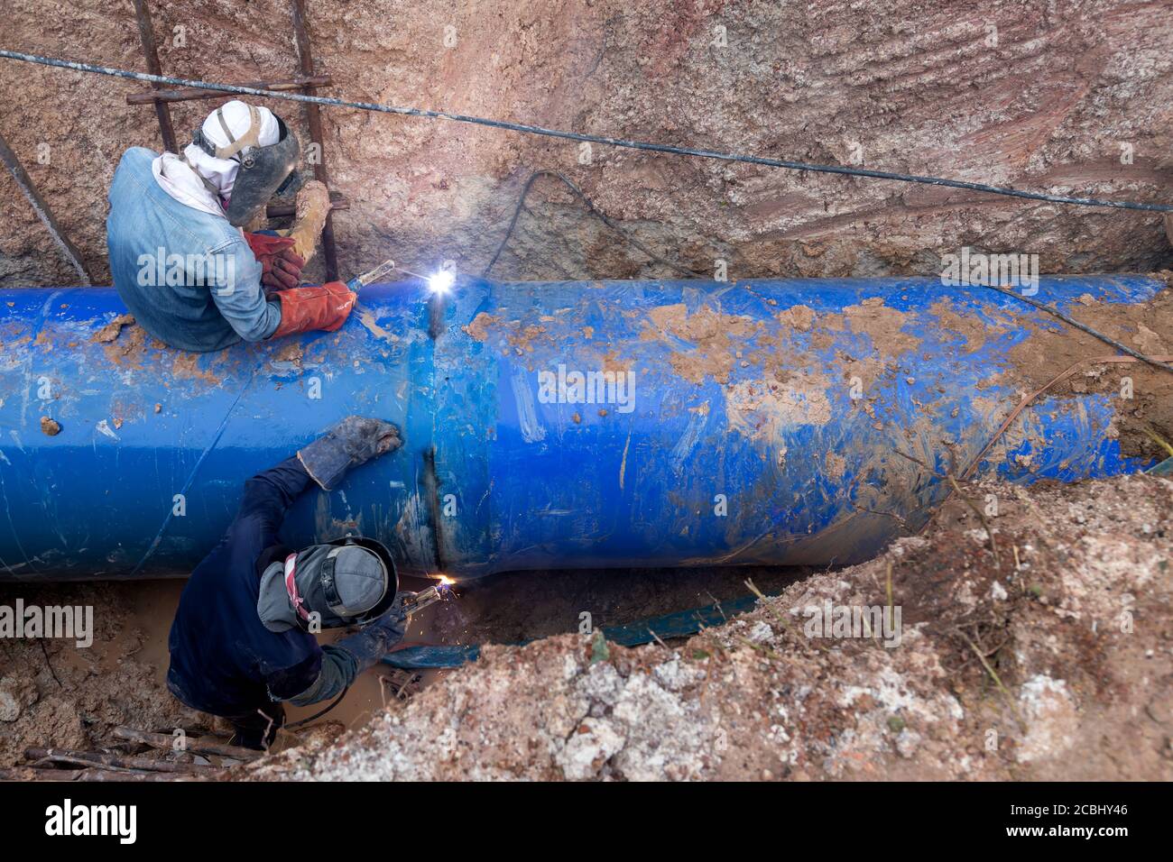 Workers weld large pipes plumbing water system underground at ...