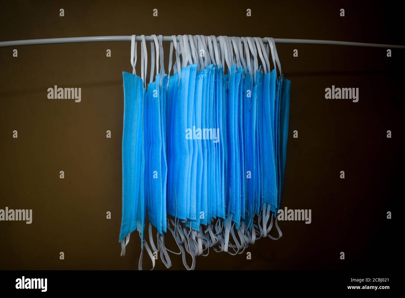A bunch of blue colored face masks are being hanged on a cloth rod for ...
