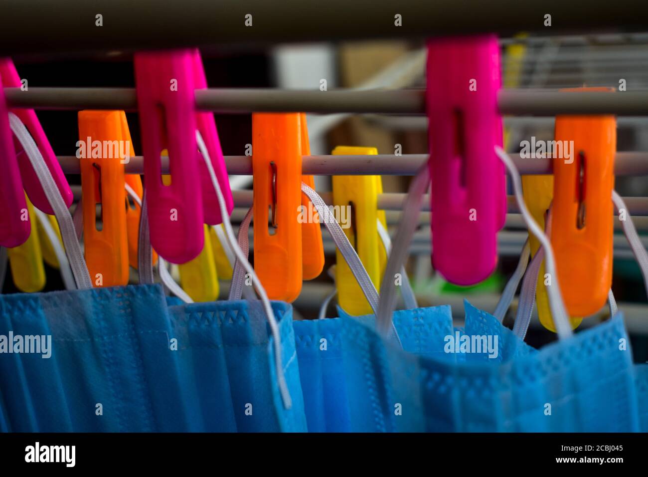 A bunch of blue colored face masks are being hanged on a cloth rod for ...