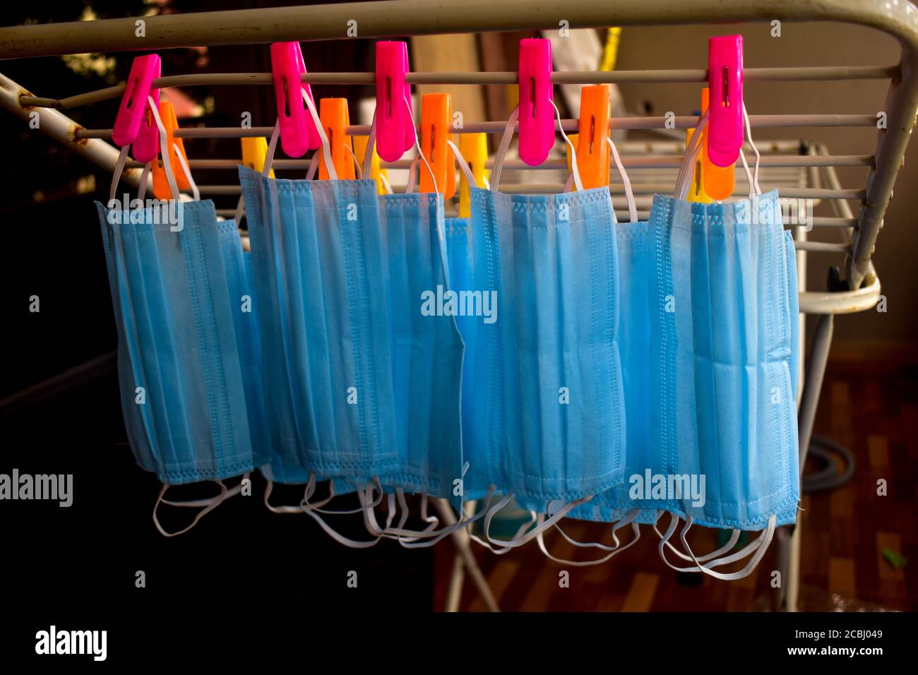 A bunch of blue colored face masks are being hanged on a cloth rod for ...