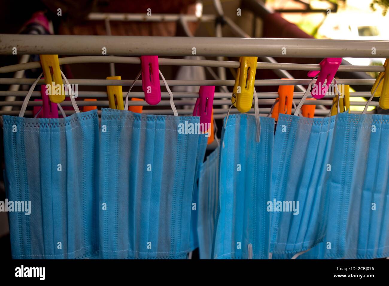 A bunch of blue colored face masks are being hanged on a cloth rod for ...