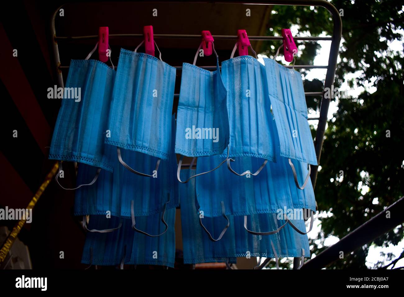 A bunch of blue colored face masks are being hanged on a cloth rod for ...