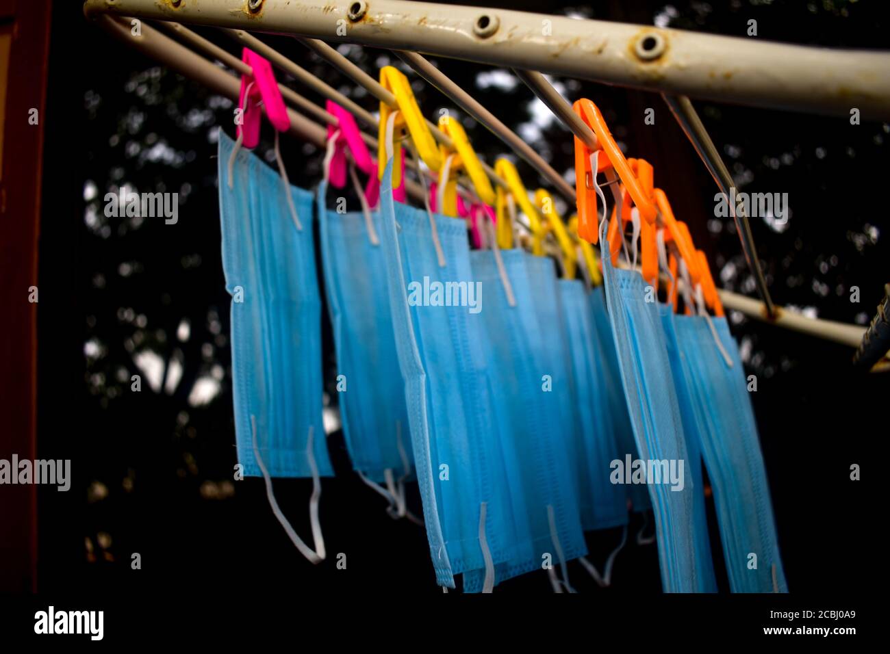 A bunch of blue colored face masks are being hanged on a cloth rod for ...