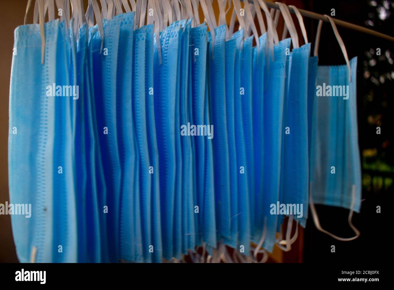 A bunch of blue colored face masks are being hanged on a cloth rod for ...