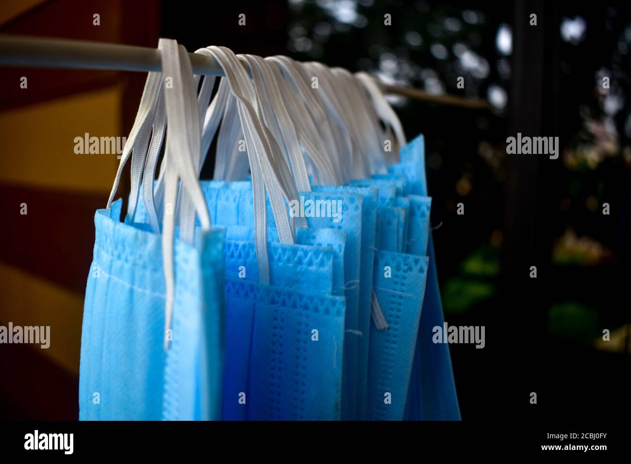 A bunch of blue colored face masks are being hanged on a cloth rod for ...
