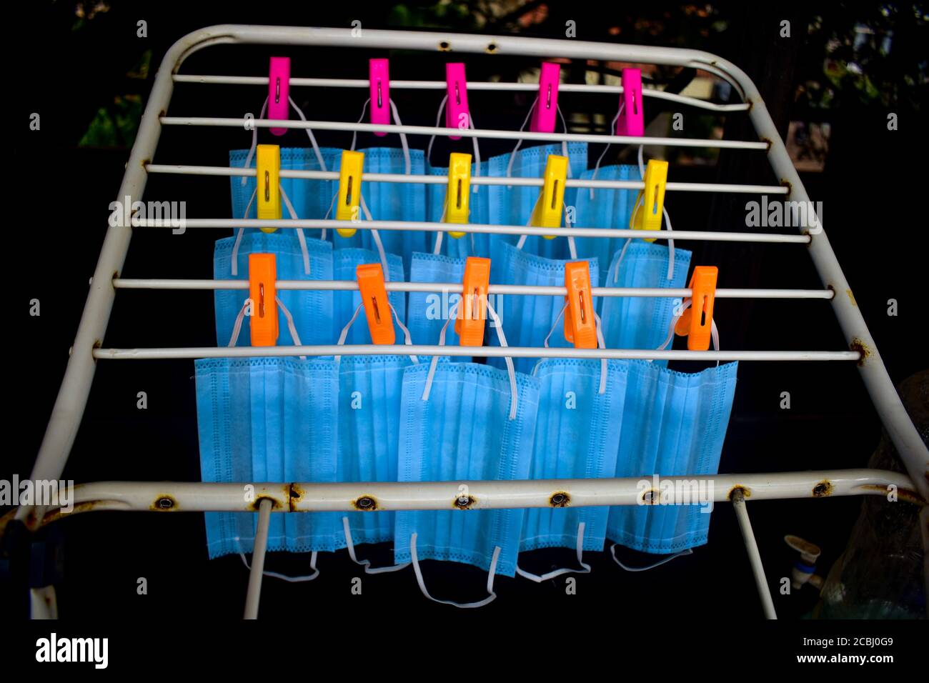 A bunch of blue colored face masks are being hanged on a cloth rod for ...