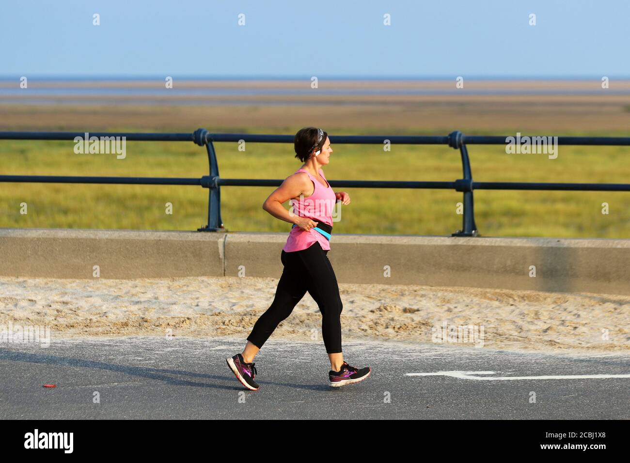 Woman jogging on the seafront promenade in Southport, Merseyside. Aug ...