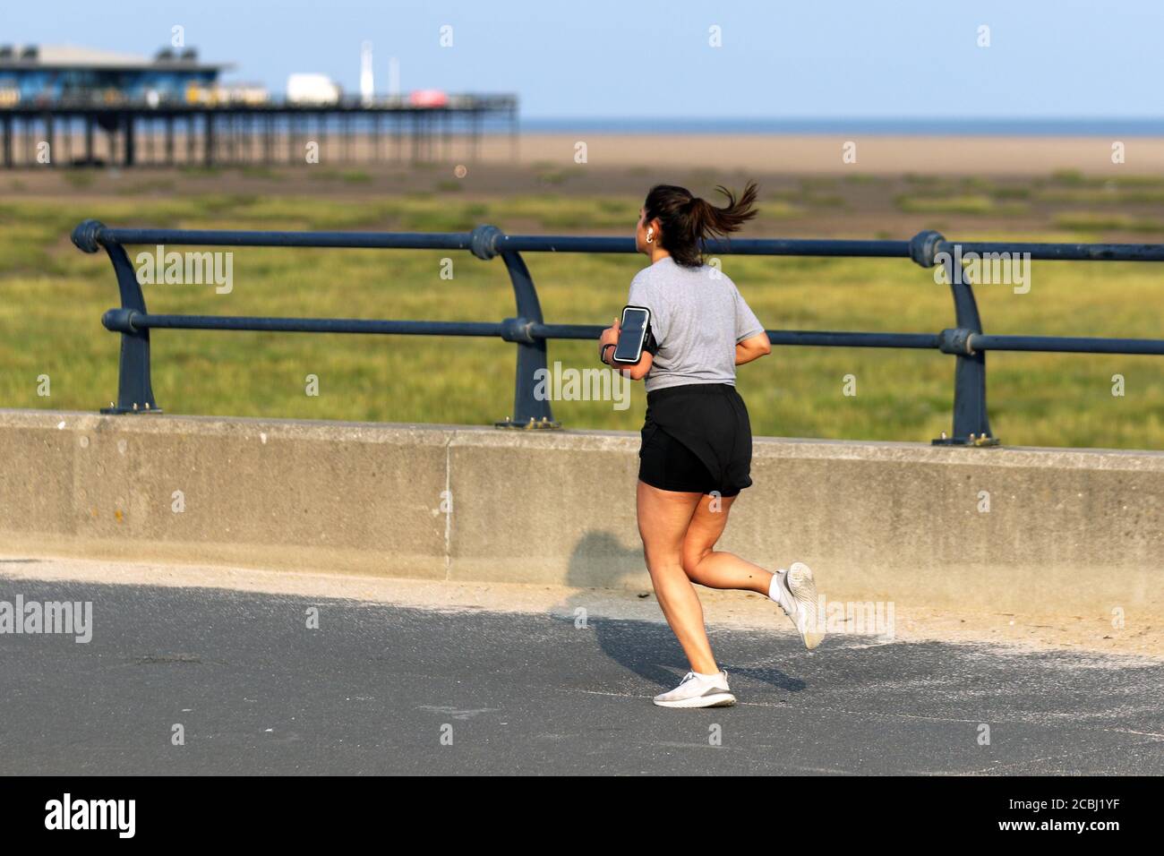 Woman jogging on the seafront promenade in Southport, Merseyside. Aug ...