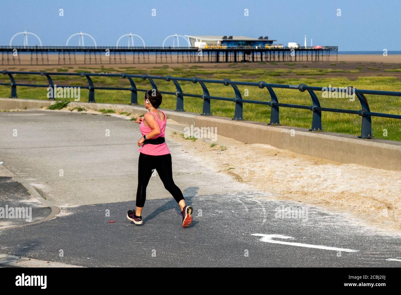 Woman jogging on the seafront promenade in Southport, Merseyside. Aug ...