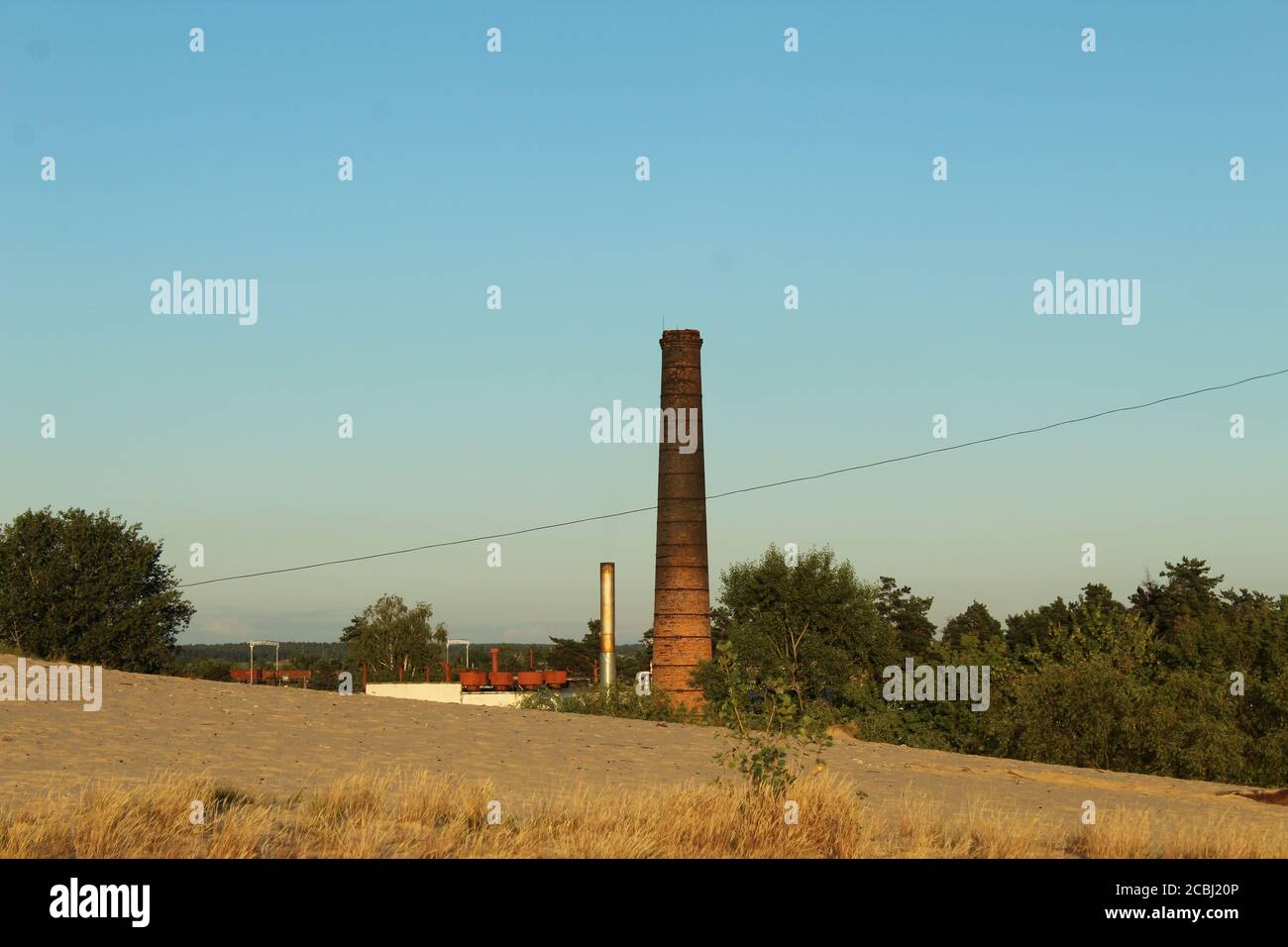 big brick boiler house chimney against the background of sand and blue ...