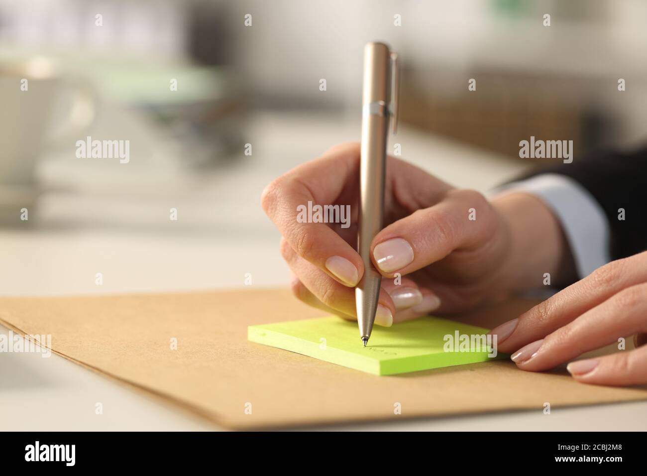 Close up of a executive woman hands writes on sticky note pad on a desk ...