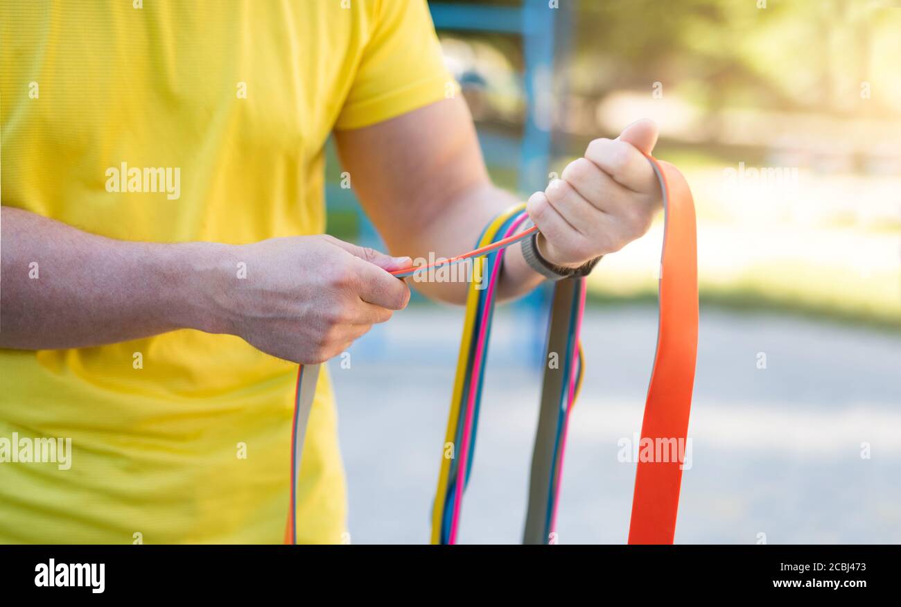 Man holding elastic rubber bands in hands outdoor Stock Photo - Alamy
