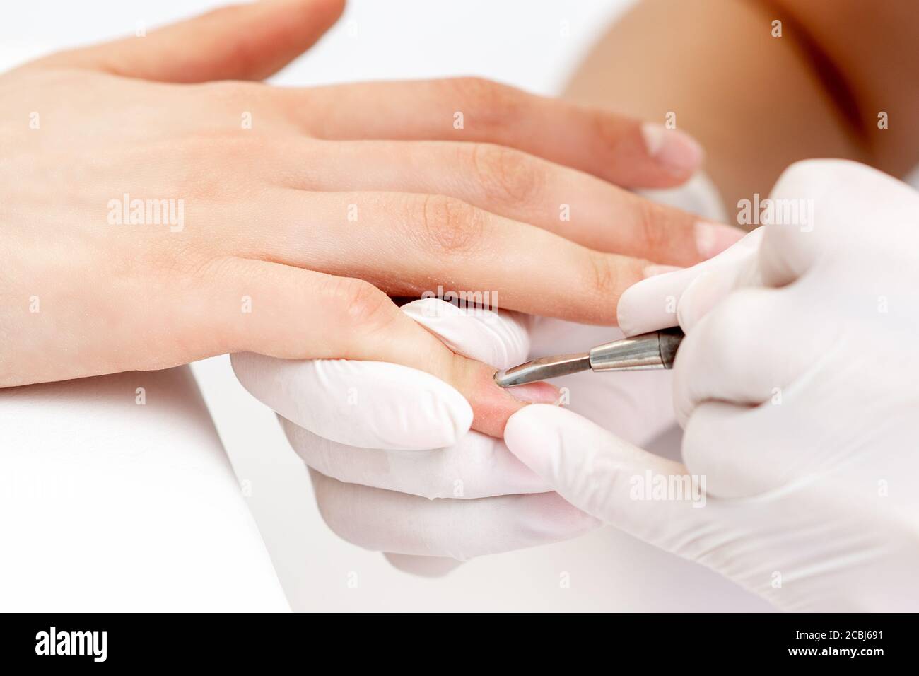 Hands of manicurist pushing cuticles on female's nails with manicure ...