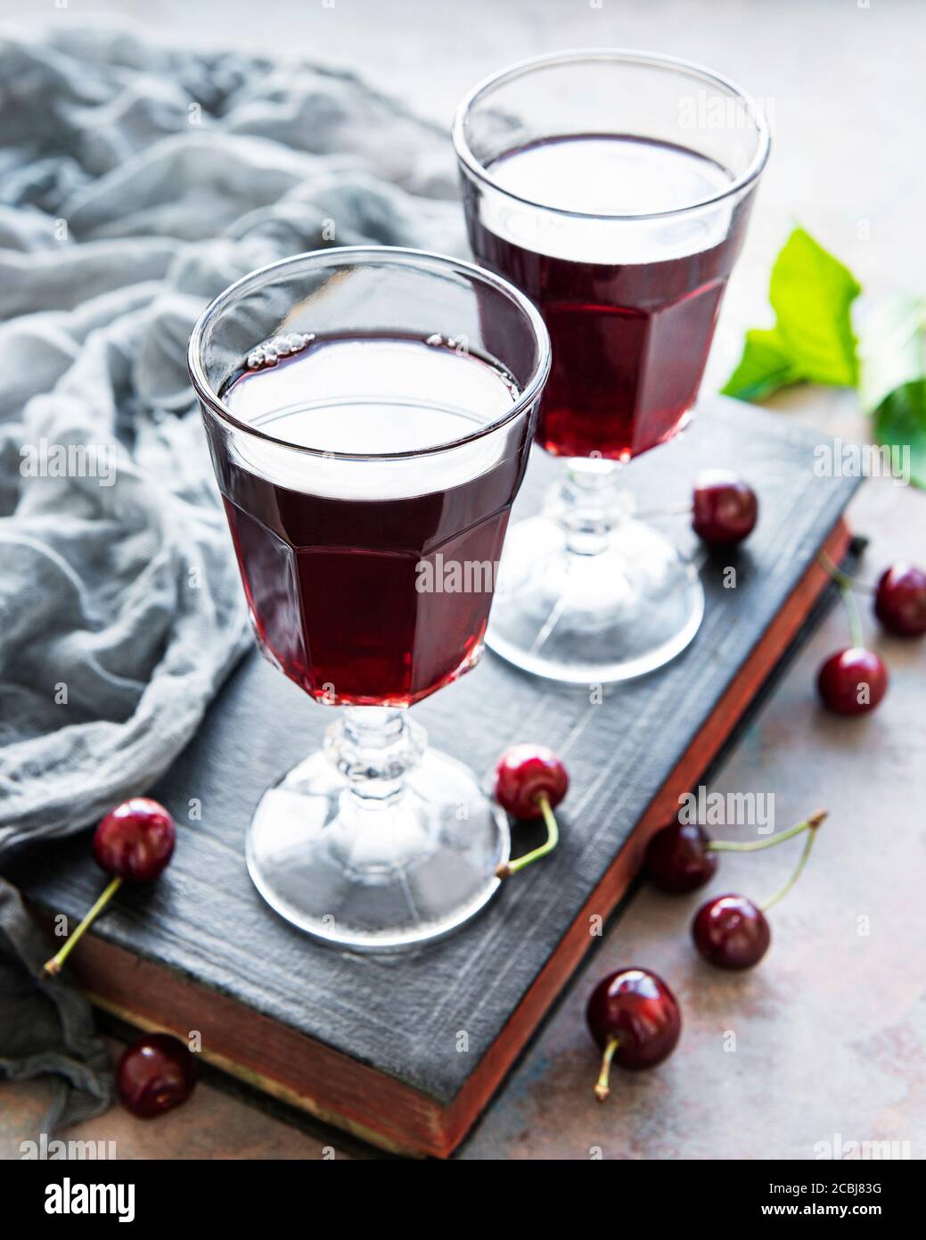 Cherry liqueur in a glass and fresh fruit on a old vintage book on a ...