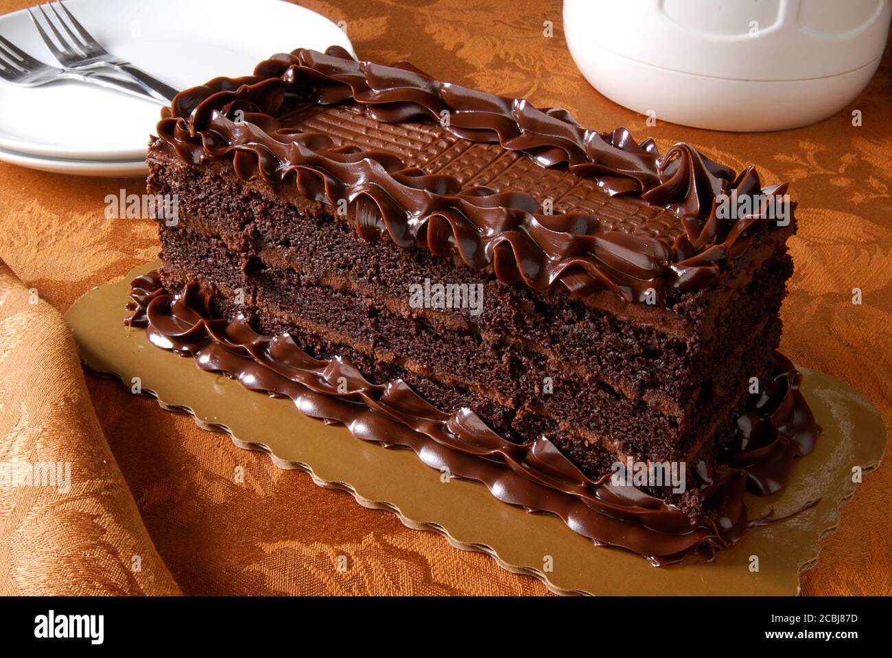 A gourmet chocolate cake with a coffee pot and serving plates Stock ...